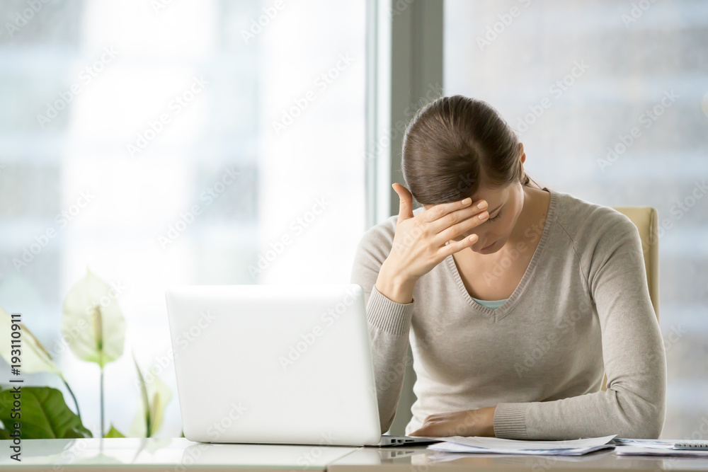 Stressed and tired female employee suffering of headache while sitting ...