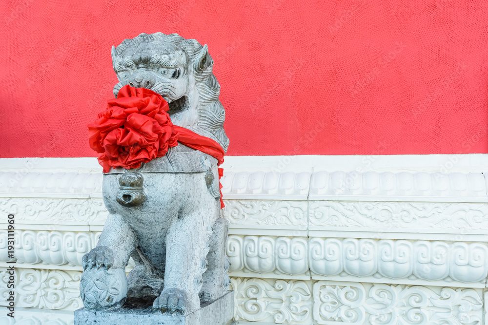 Traditional stone statue of a chinese guardian lion (male), wearing a ...