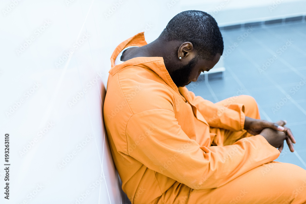 sad african american prisoner sitting on bench in prison cell Stock ...