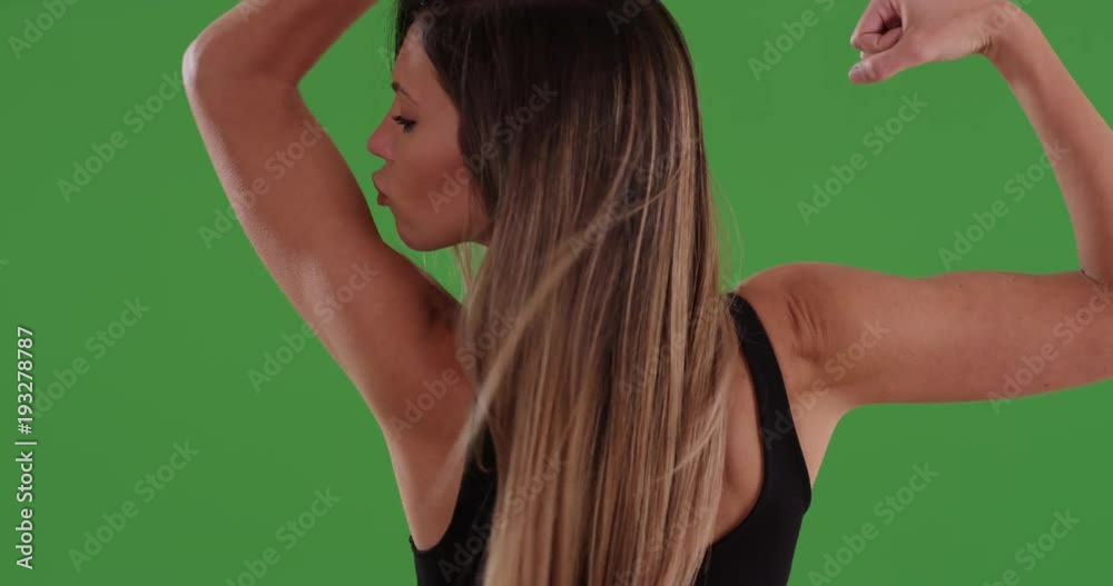 Rear view of athletic young millennial woman flexing biceps and kissing ...