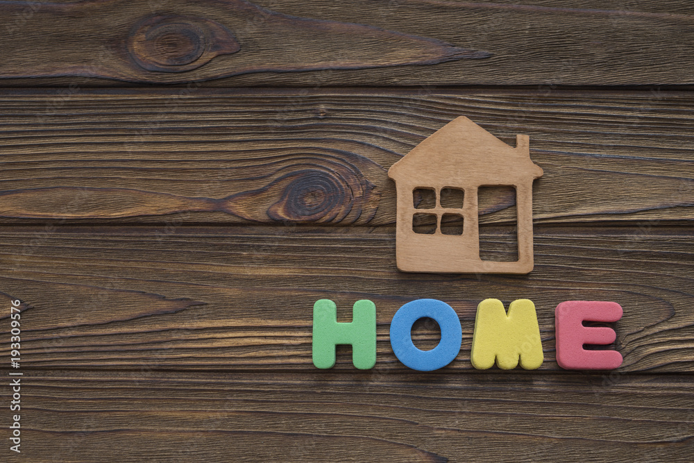 symbol of a house and colored text on a wood texture background. idea ...