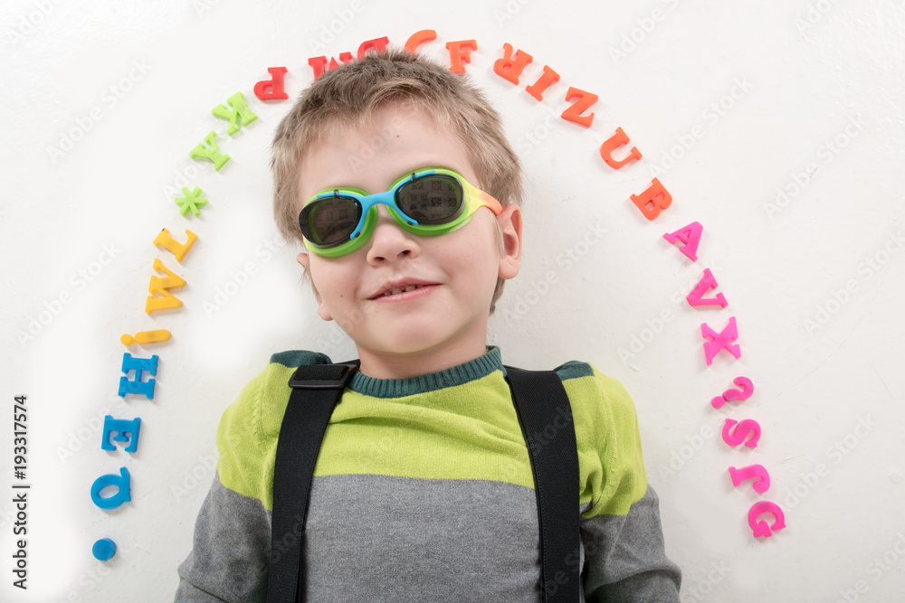 Happy charming Caucasian blond kid in colored clothes playing with ...
