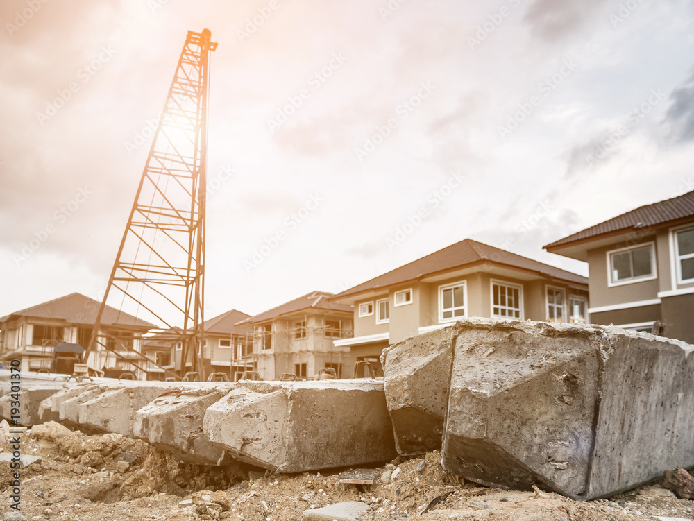 house building at construction site with pile driver and concrete piles ...