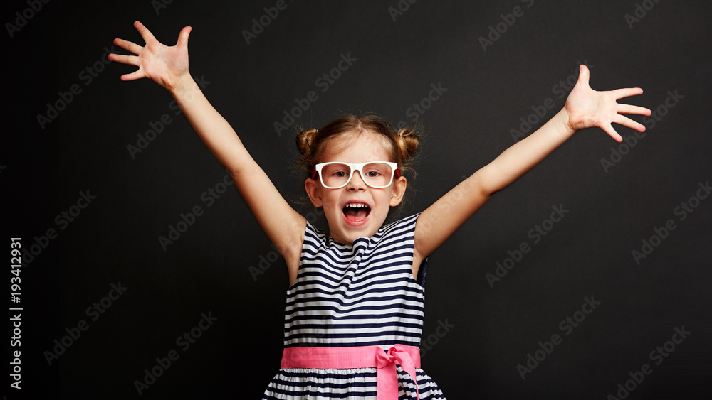 Happy little girl winning success. Cute kid standing with hands up and ...