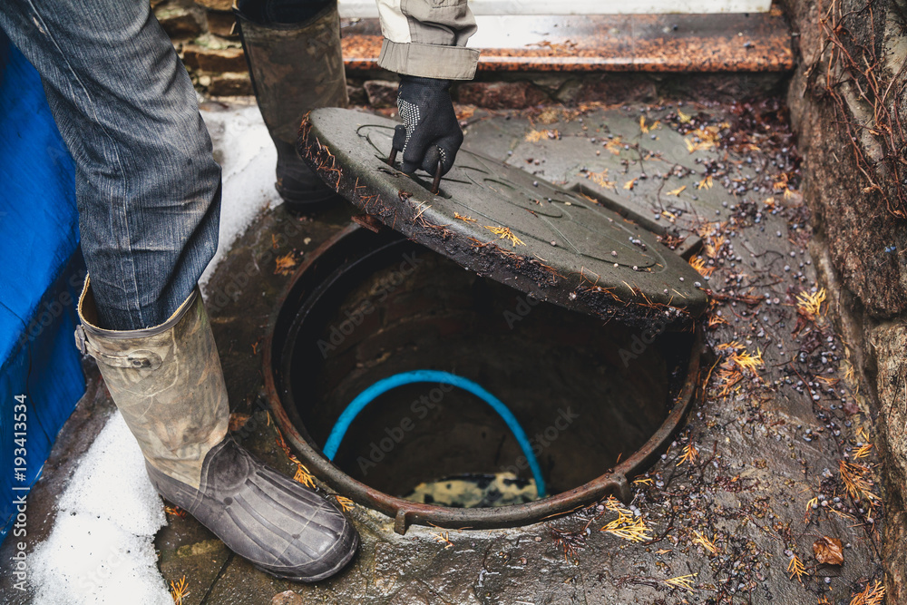 hand opens sewer hatch in yard Stock Photo | Adobe Stock