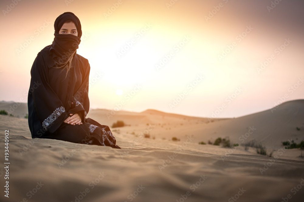 Young woman Bedouin in black traditional clothes against sunset sky ...