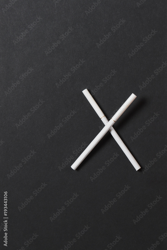 Two crossed white cigarettes like letter X on black background. Health ...
