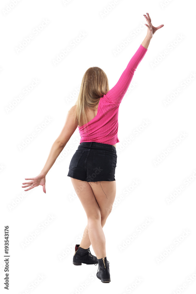 Back view of blonde woman in pink shirt dancing in stretched arms pose ...