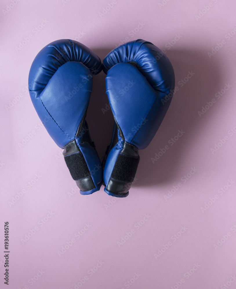 on a pink background two boxing gloves of blue color in the sight of ...