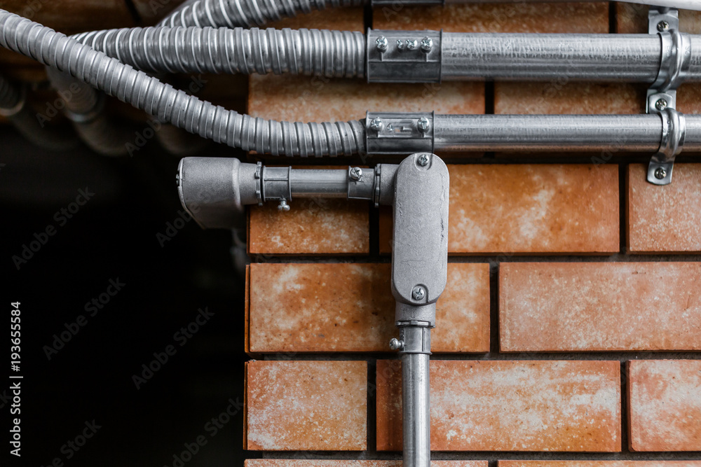 steel pipe electricity system work on brown brick wall background ...
