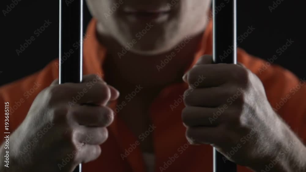 Cruel serial killer holding jail cell bars, prisoner hands closeup, law ...