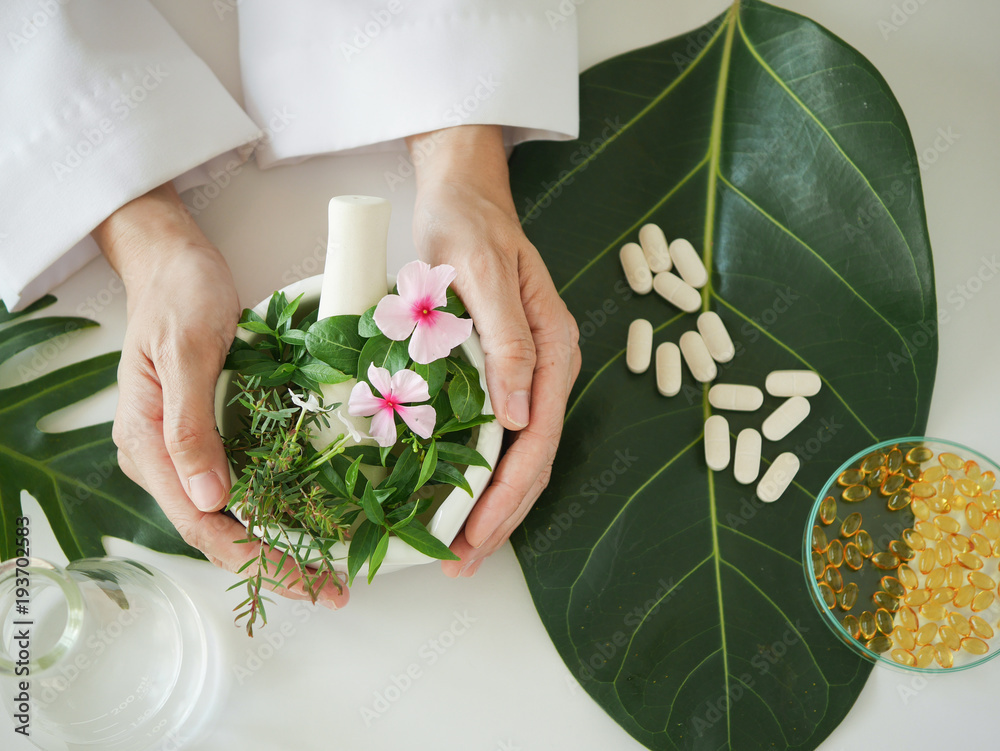 scientist or doctor making herbal medicine with herb leaves , capsule ...