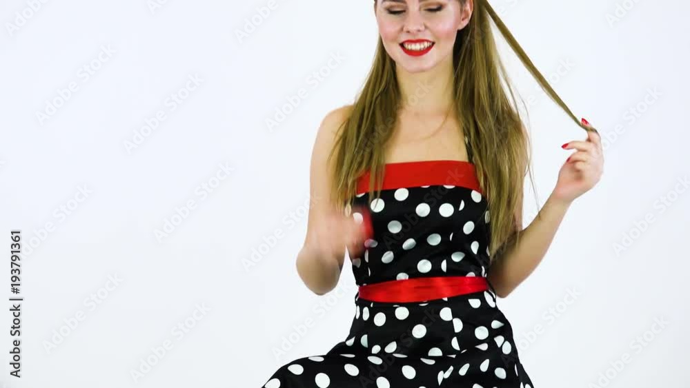 A beautiful 50s pin-up girl sits on a stool, moves in rhythm of music ...