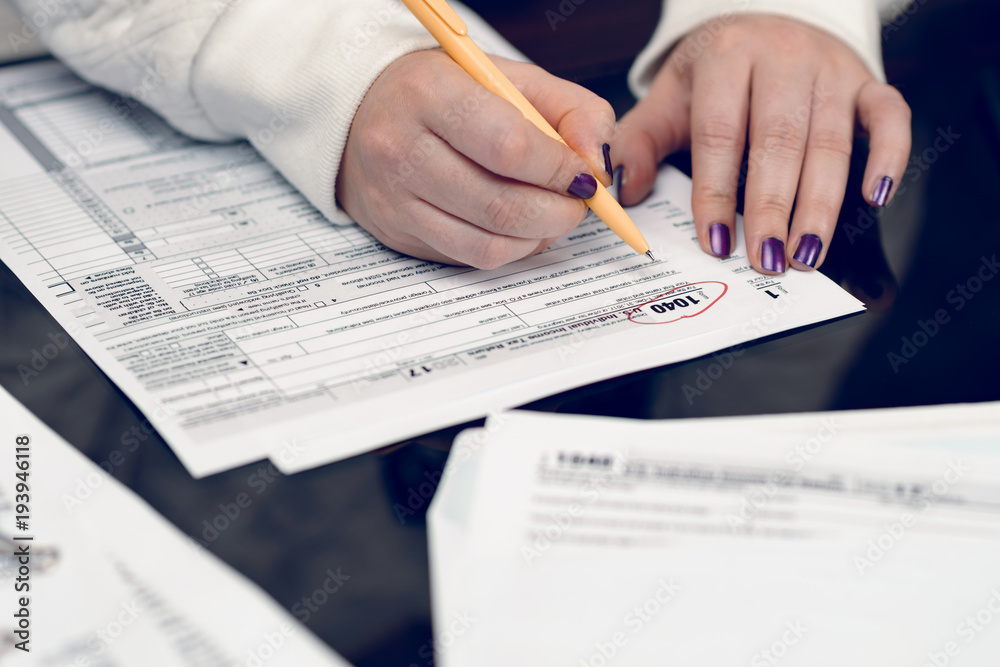 Woman fills the tax form, working with tax documents.Form 1040 ...