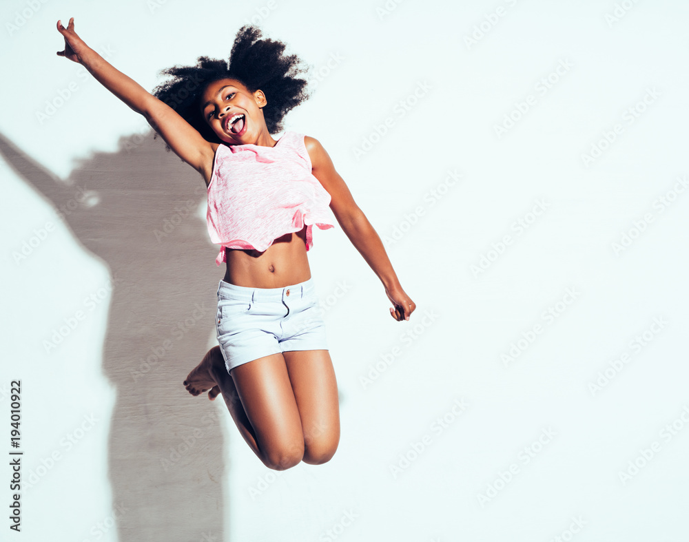 Cute young African girl jumping enthusiastically into the air Stock ...