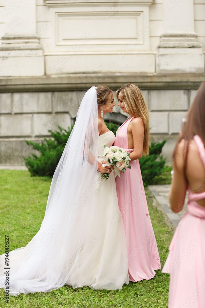 Wedding blogger make photo of bride and bridesmaid who embracing after ...