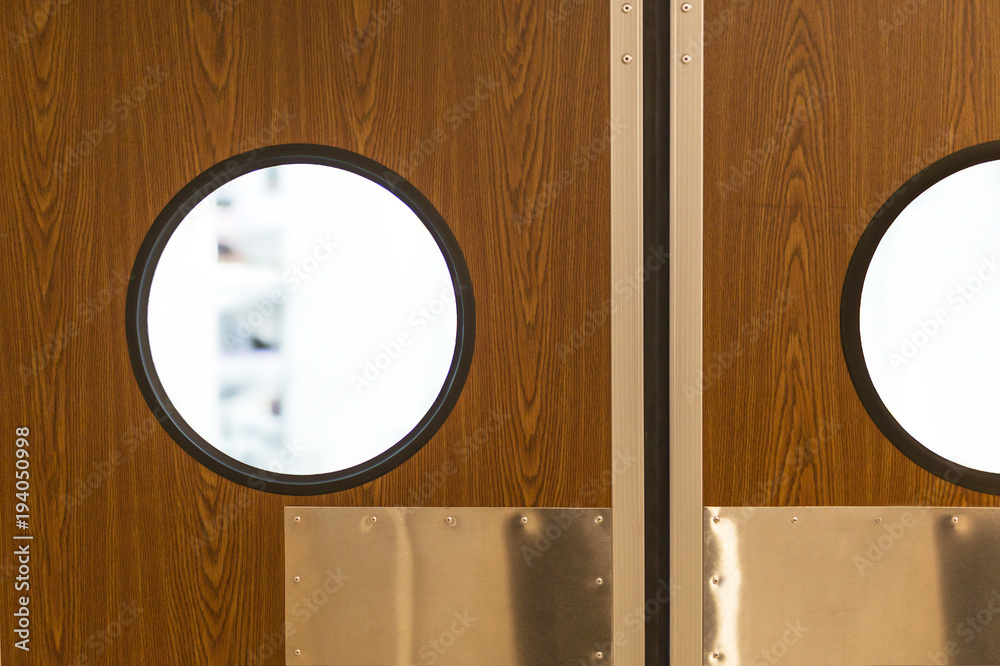 Restaurant kitchen entrance. Closed wooden double door with round ...