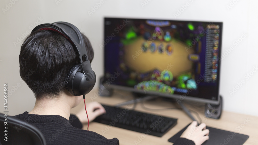 gamer playing pc game wearing headphone. Stock Photo | Adobe Stock