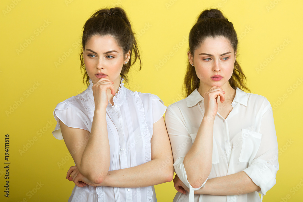 two beautiful young girl sisters twins in white blouses on a yellow ...