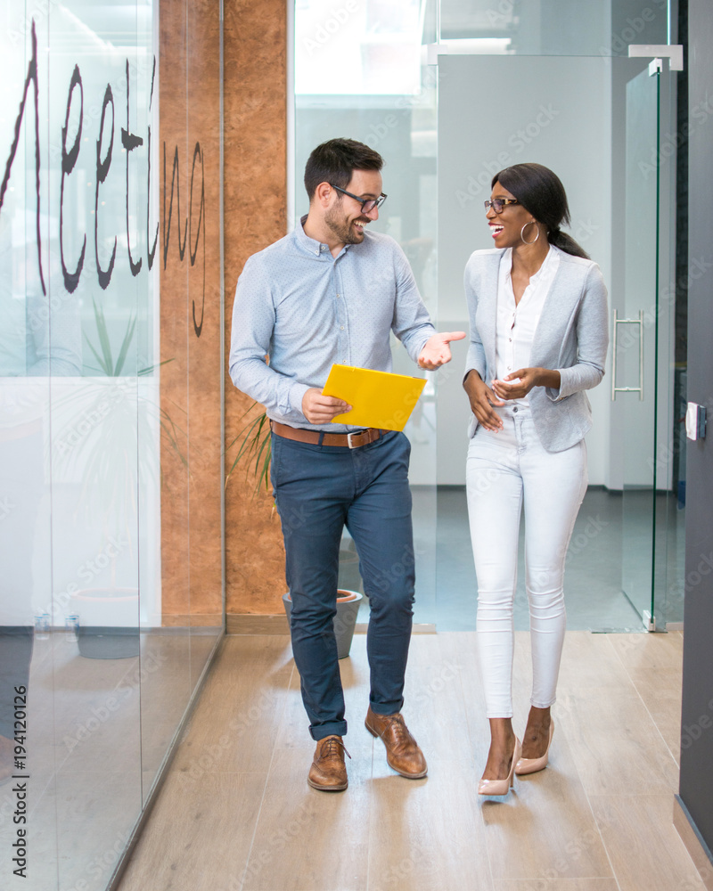Two smiling business people walking through office hall and talking ... Two smiling business people walking through office hall and talking ...