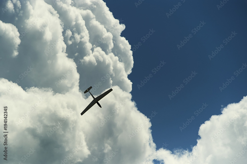 A Glider flying in blue sky with big white clouds. The glider is a ...