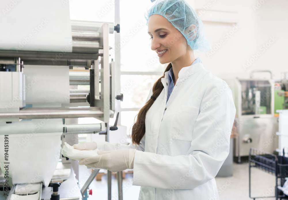 Side view of a happy manufacturing employee wearing white lab coat ...