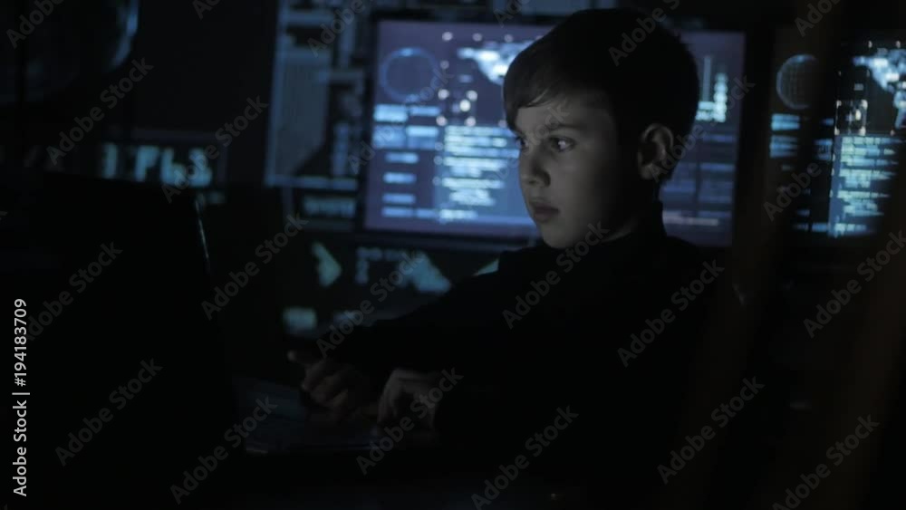 young prodigy boy hacker programmer working at the computer in the data ...