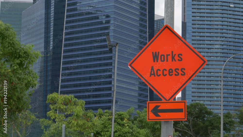 CLOSE UP Works access sign in front of tall glassy skyscrapers in ...