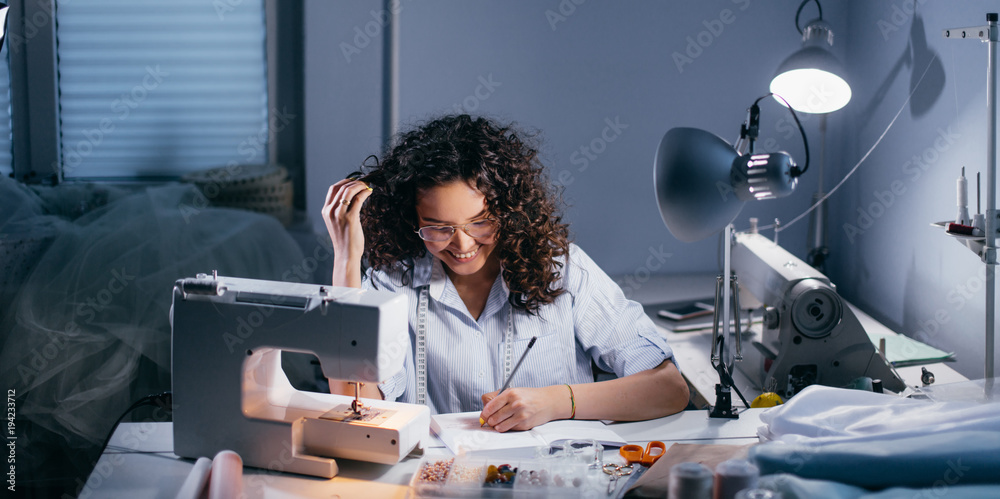 laughing female tailor is making a draft indoors. drawing by sight ...