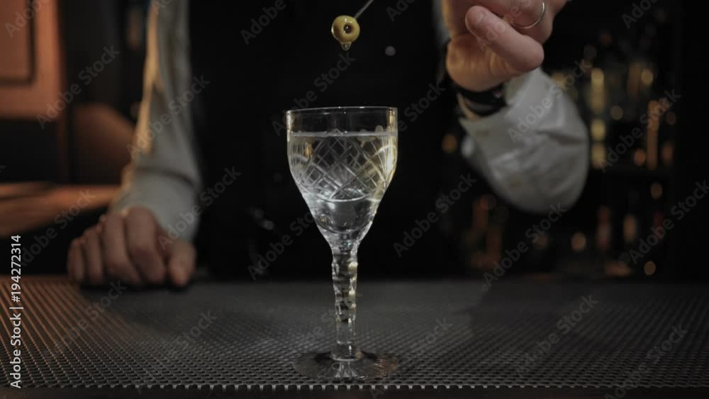 Cinemagraph of bartender holding up olive on sword stick over fancy and ...