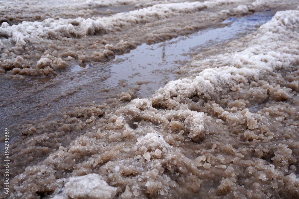 The snow melts on the road and turns into a puddle and slush in the ...