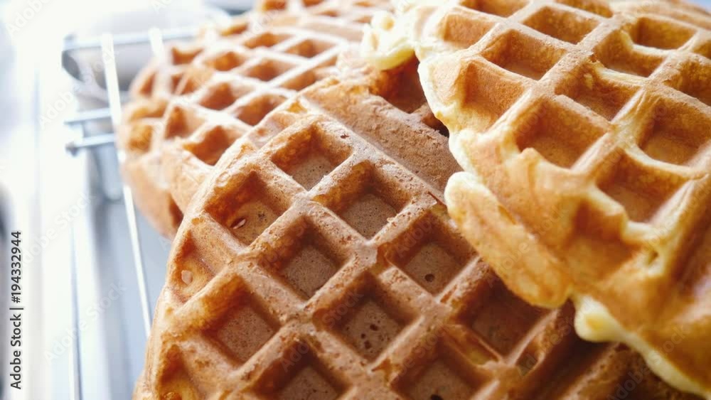 Putting a golden brown waffle on a stack of waffles to cool in 4k. The ...