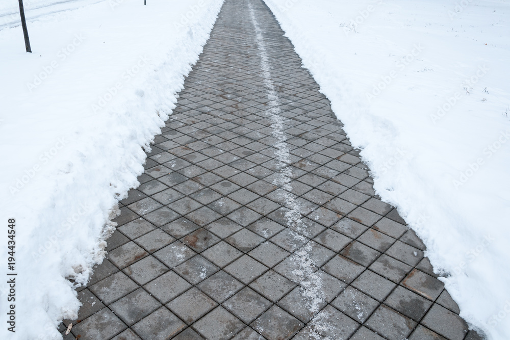 Pedestrian sidewalk or walkway path with tiles cleaned of snow in the ...