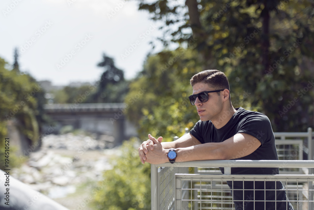 Male with sunglasses lean on banister at the river. Handsome gazing ...