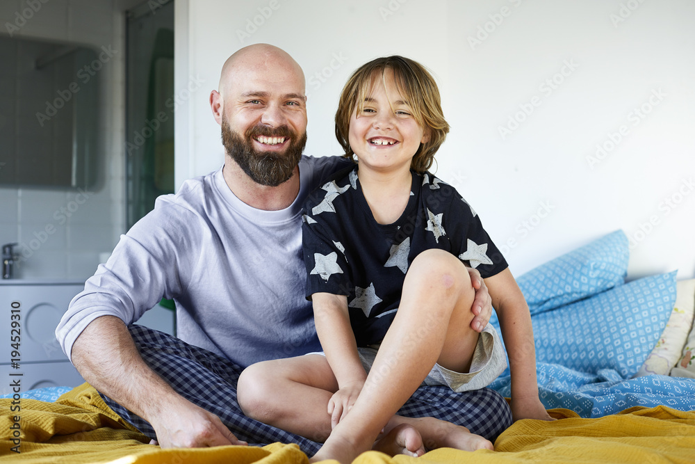Smiling Boy Sitting On Father's Lap In Bedroom Stock Photo | Adobe Stock