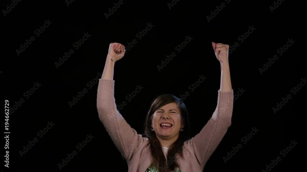 An attractive young lady wearing a pink sweater with her arms up in the ...