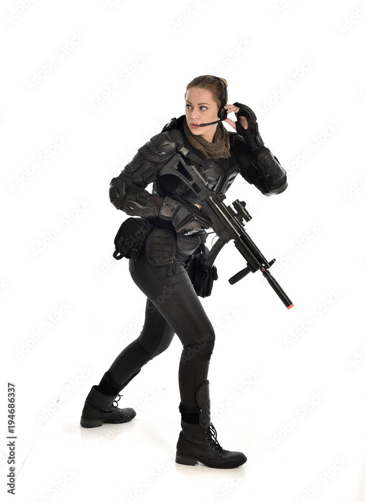 full length portrait of female soldier wearing black tactical armour ...
