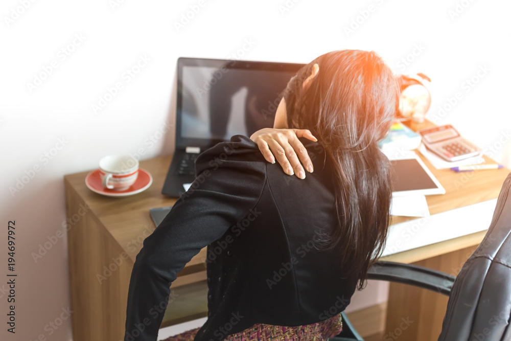 Rear of businesswooman suffering from shoulder pain in the office Stock ...