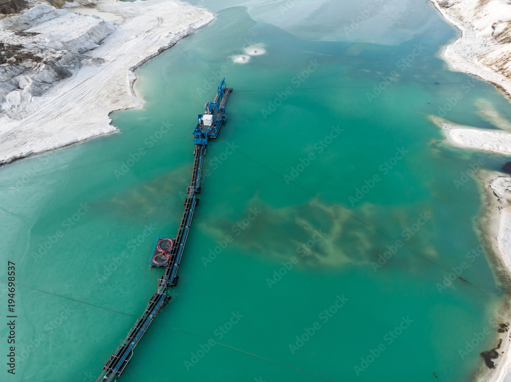 Aerial view of the long boom of a suction excavator in a quartz quarry ...
