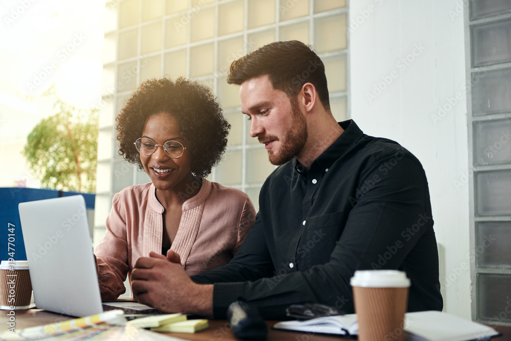 Smiling colleagues working online together at an office desk Stock ...