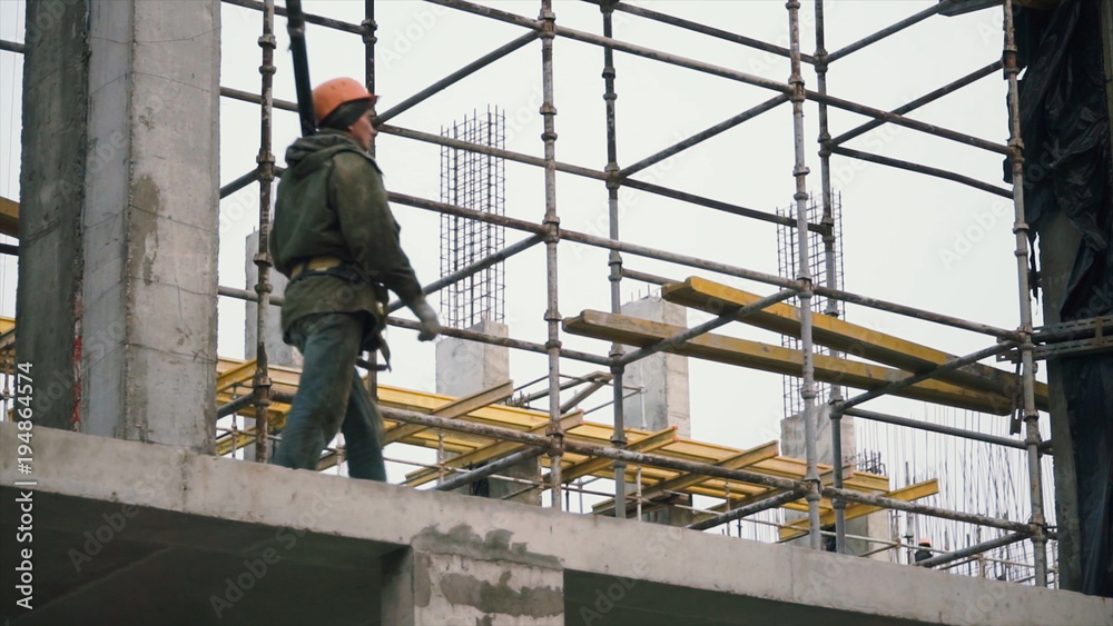 Construction workers on site holding pipe. Clip. A man goes with a pipe ...