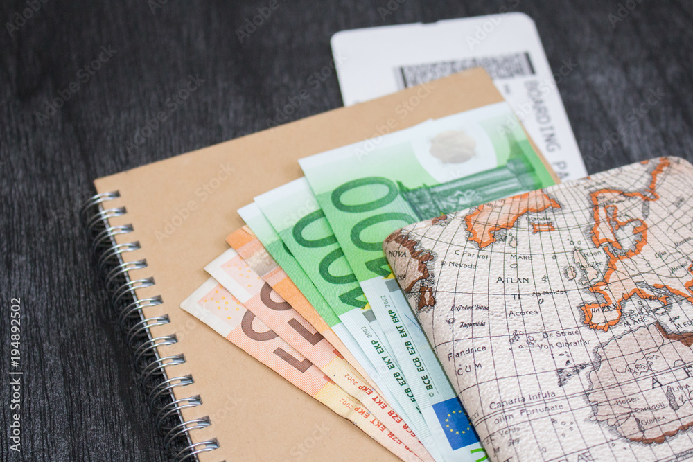 Euro banknotes on notepad and boarding pass. The money is on the craft ...