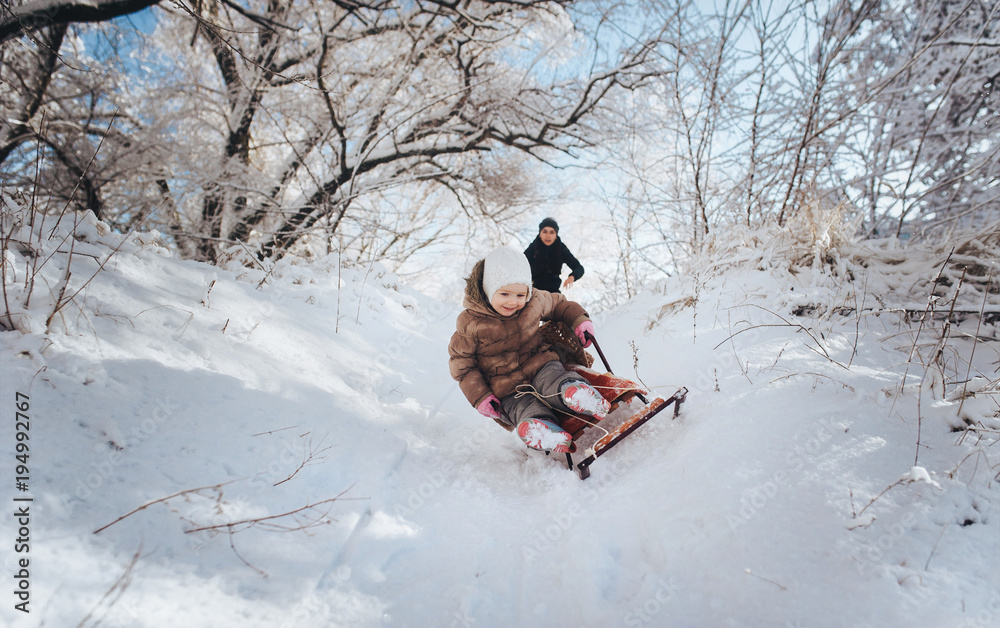 The little girl is falling from the sled. Mother worries about the ...