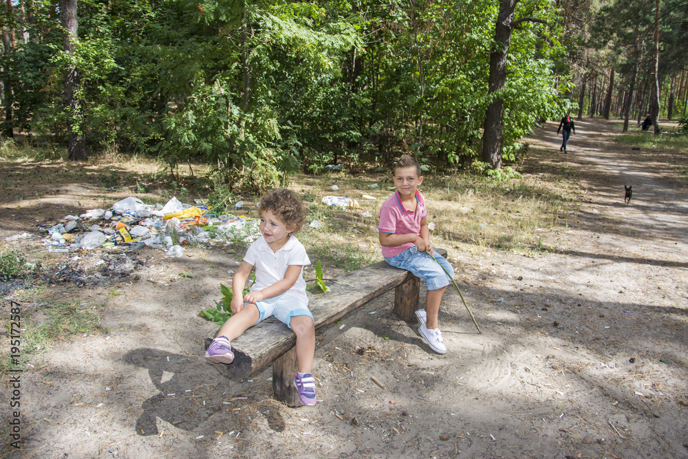 In the summer in the forest, small children play near the garbage dump ...