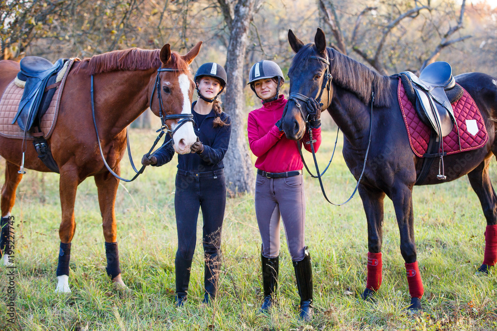 Two teenage girls with their horses in autumn park. Equestrian sport ...