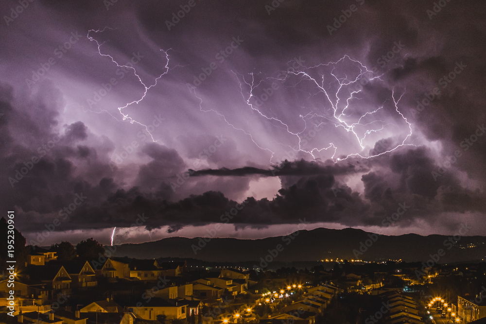 The furious lightning falling next to a quiet town. Magical lights and ...