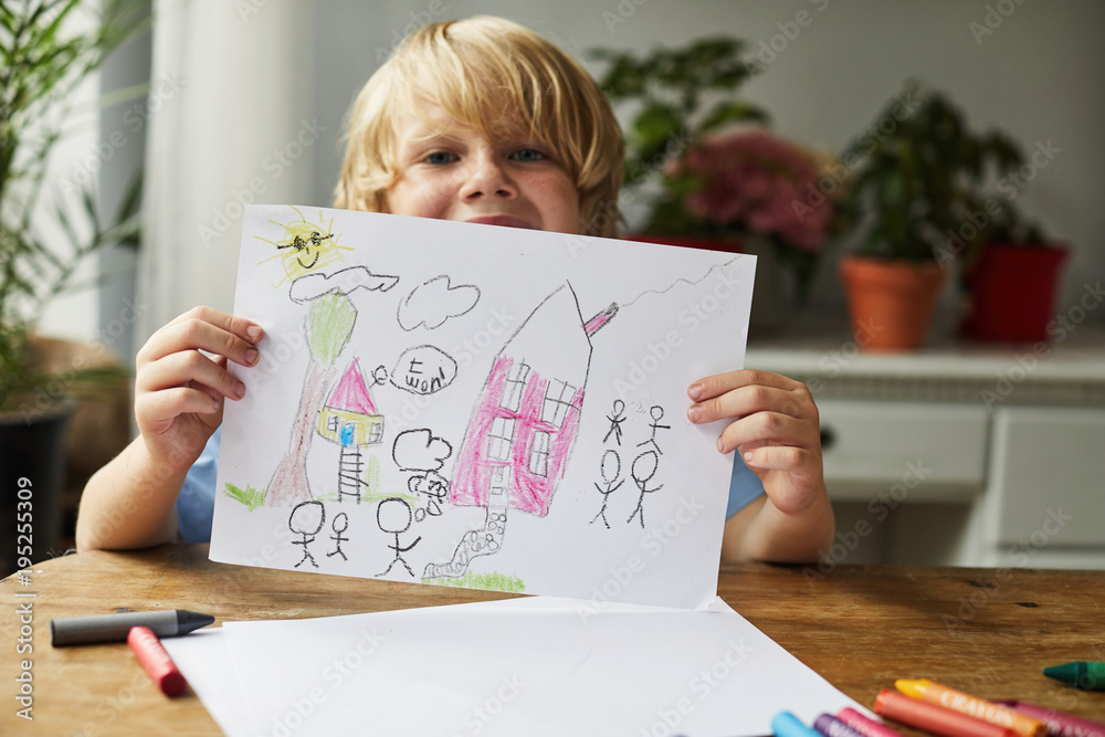 Portrait of boy holding a drawing of a house and family Stock Photo ...