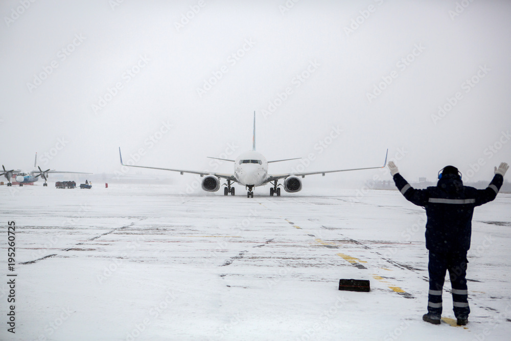 Member of ground crew park passenger airliner on airport apron in ...