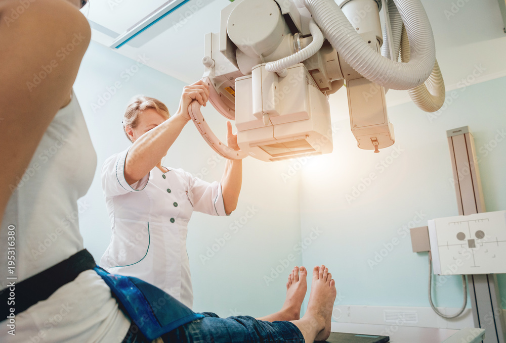 Radiologist and patient in a x-ray room. Classic ceiling-mounted x-ray ...