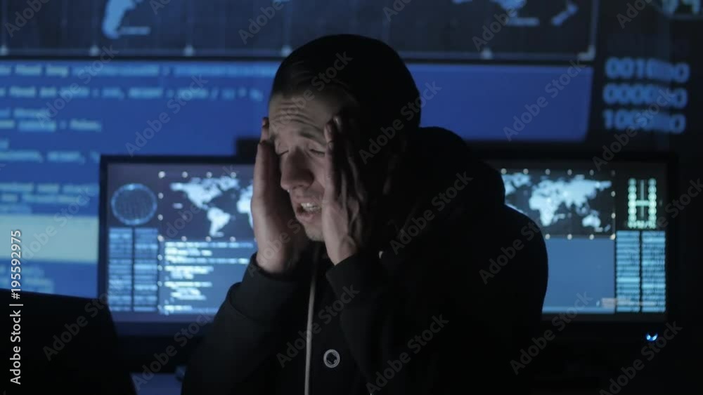Male geek hacker overworking at computer and suffers from a headache in ...